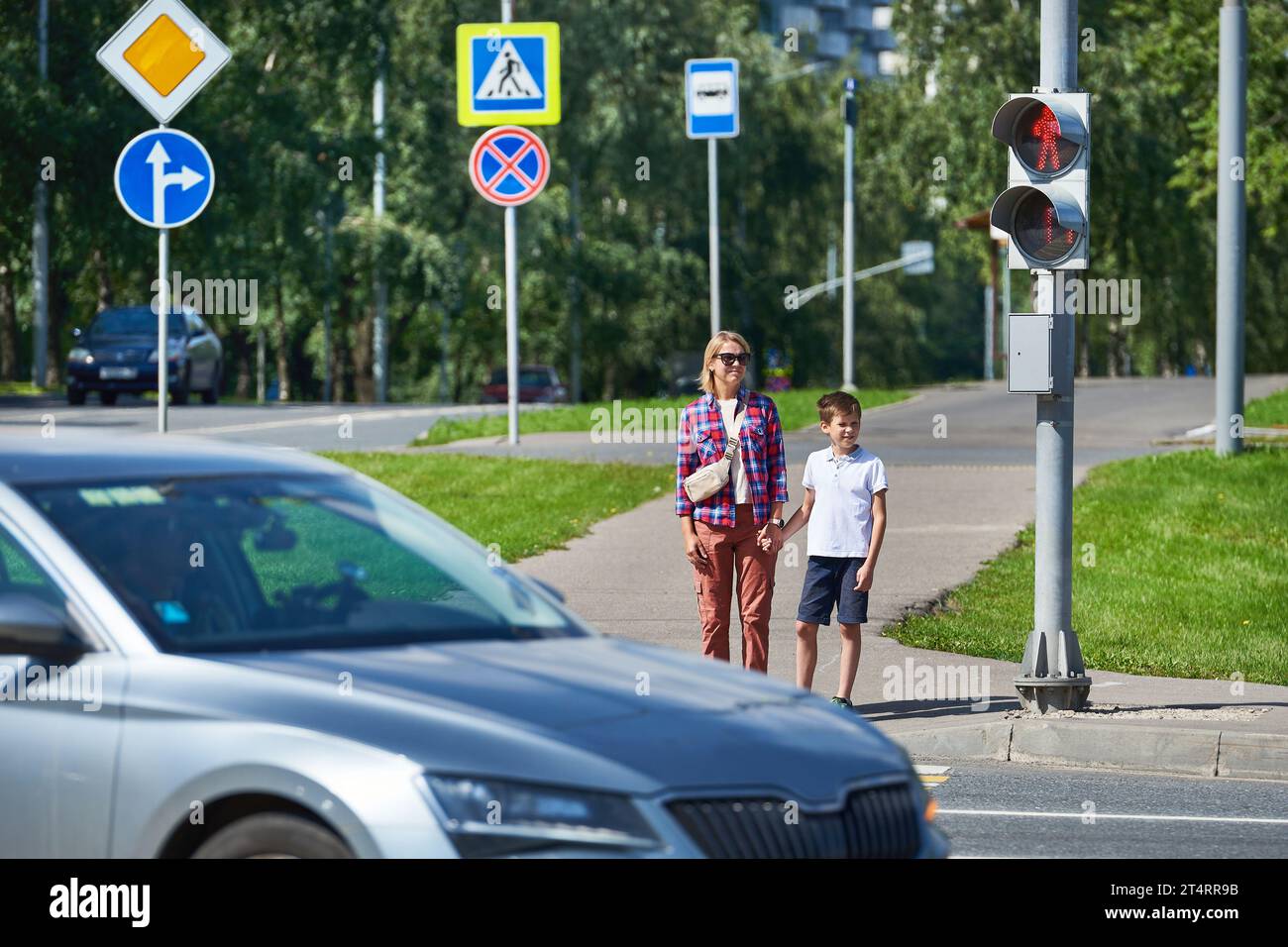 Woman with child by the road at a pedestrian crossing and traffic light ...