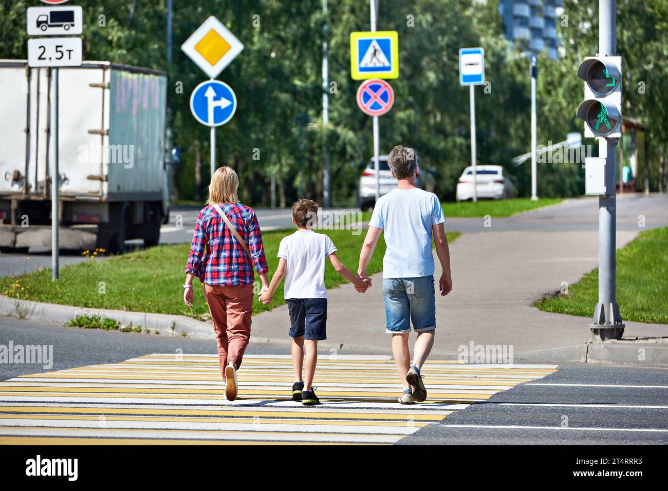 Family, woman, man and child cross the road at a pedestrian crossing ...
