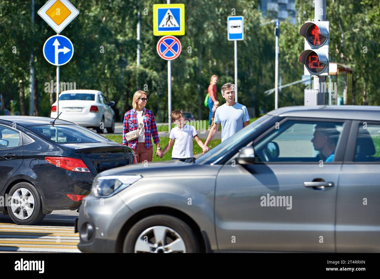 Family, woman, man and child cross the road at a pedestrian crossing ...