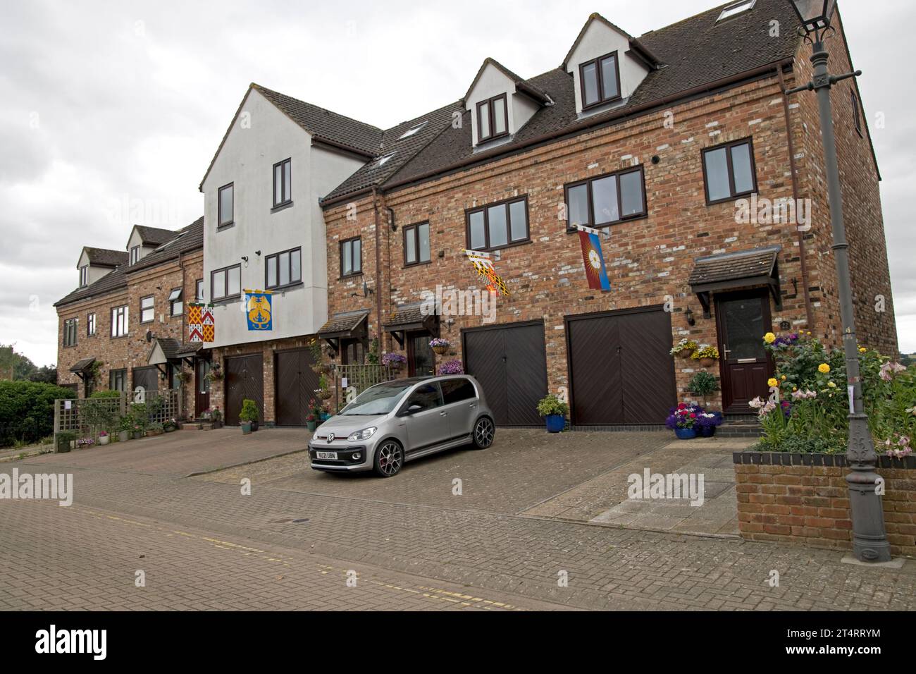Modern tredbirck terraced houses with dormers above and garages below ...