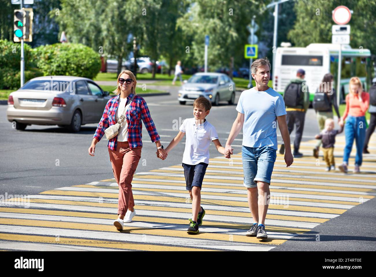 Family, woman, man and child cross the road at a pedestrian crossing ...