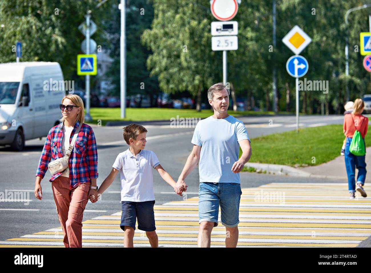 Family, woman, man and child cross the road at a pedestrian crossing ...