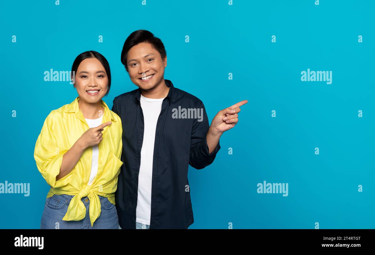 Happy young asian man in casual and lady point fingers at free space ...