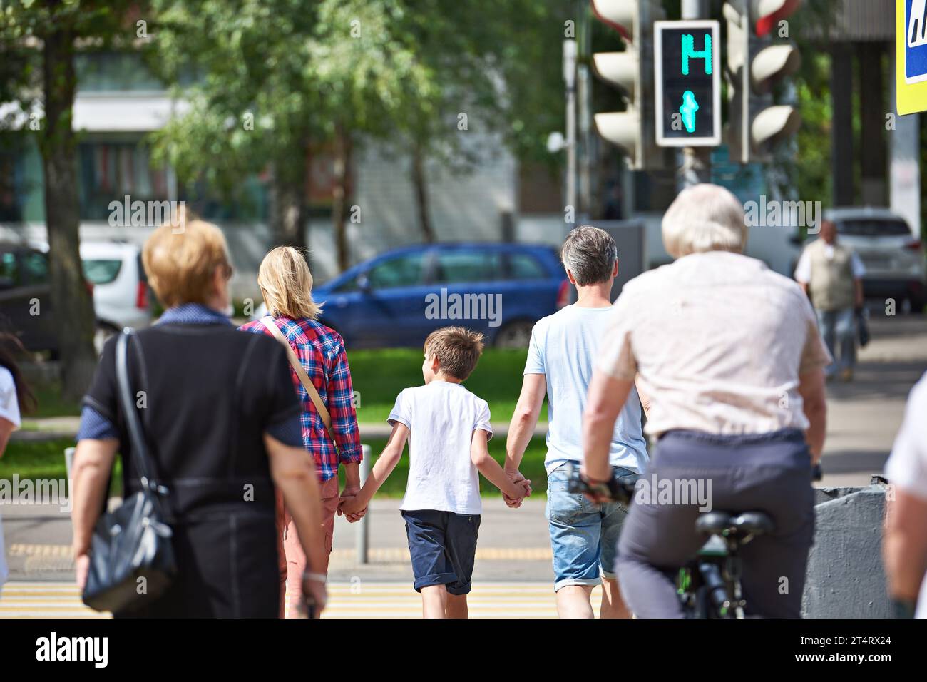 Family, woman, man and child cross the road at a pedestrian crossing ...