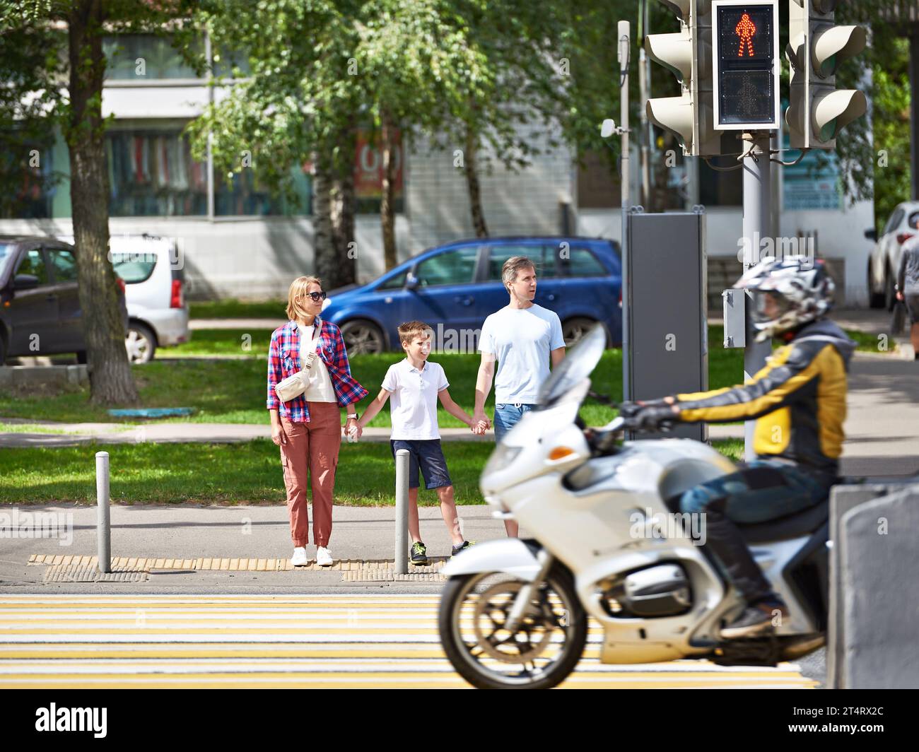 Family, woman, man and child cross the road at a pedestrian crossing ...