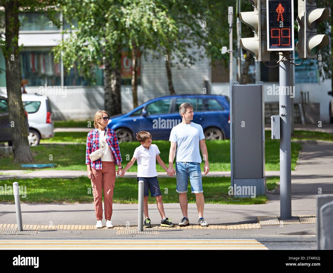 Family, woman, man and child cross the road at a pedestrian crossing ...