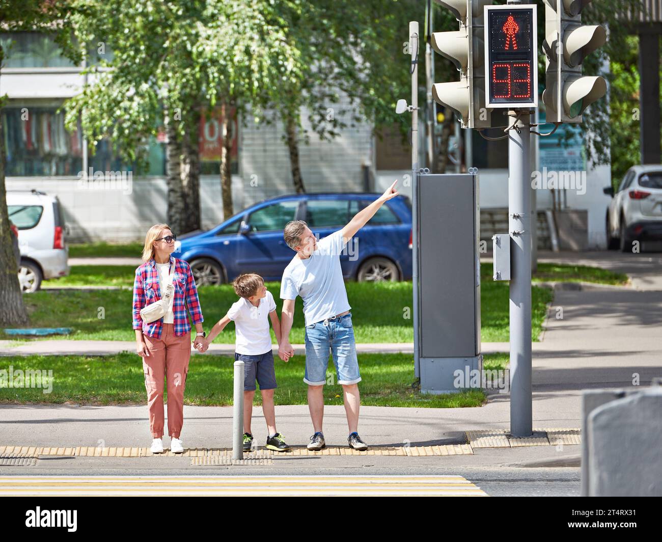 Family, woman, man and child cross the road at a pedestrian crossing ...