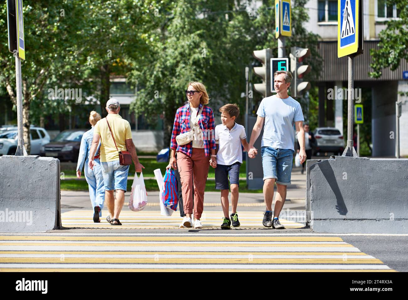 Family, woman, man and child cross the road at a pedestrian crossing ...