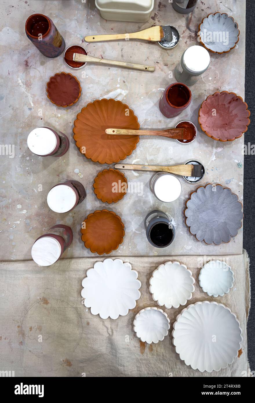 Handmade ceramic scallop plates and bowls being glazed in various ...