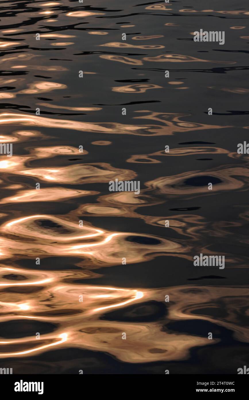 Water ripples and waves reflect the summer sun made hazy and dark by ...