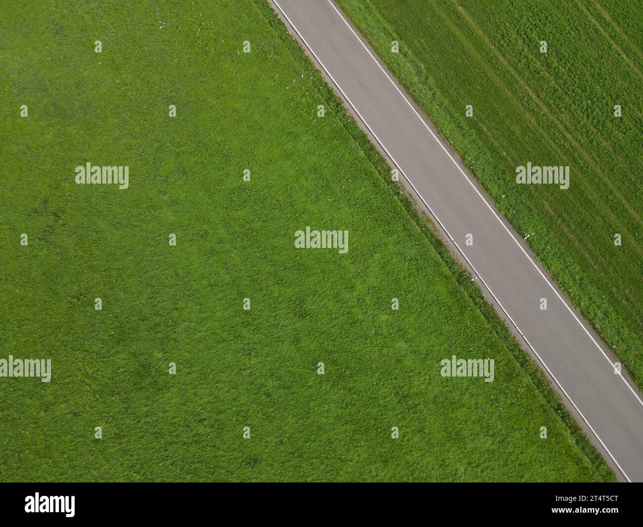 Aerial view of a straight road between grass fields in the landscape ...
