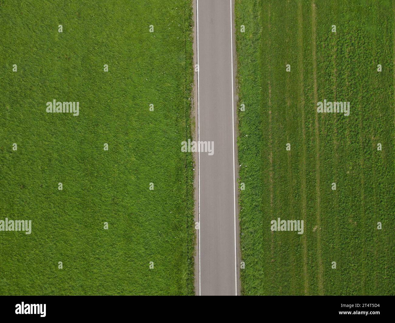 Aerial view of a straight road between grass fields in the landscape ...