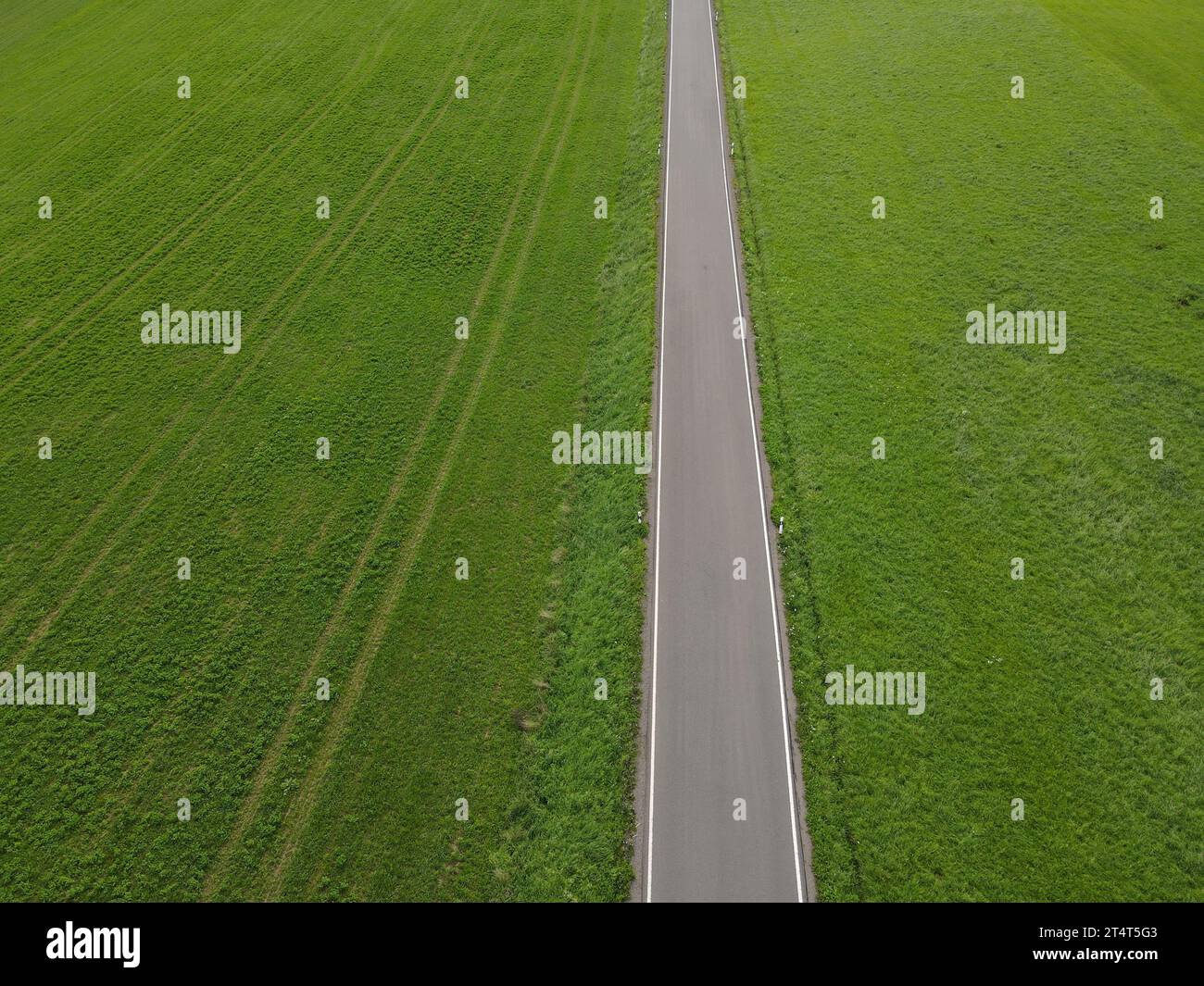 Aerial view of a straight road between grass fields in the landscape ...