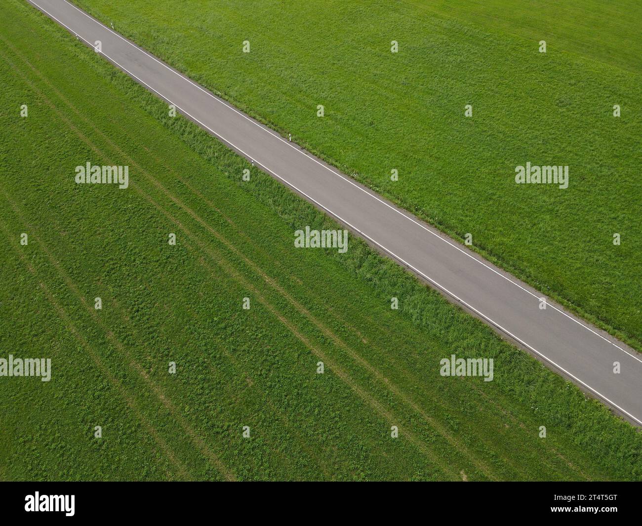 Aerial view of a straight road between grass fields in the landscape ...