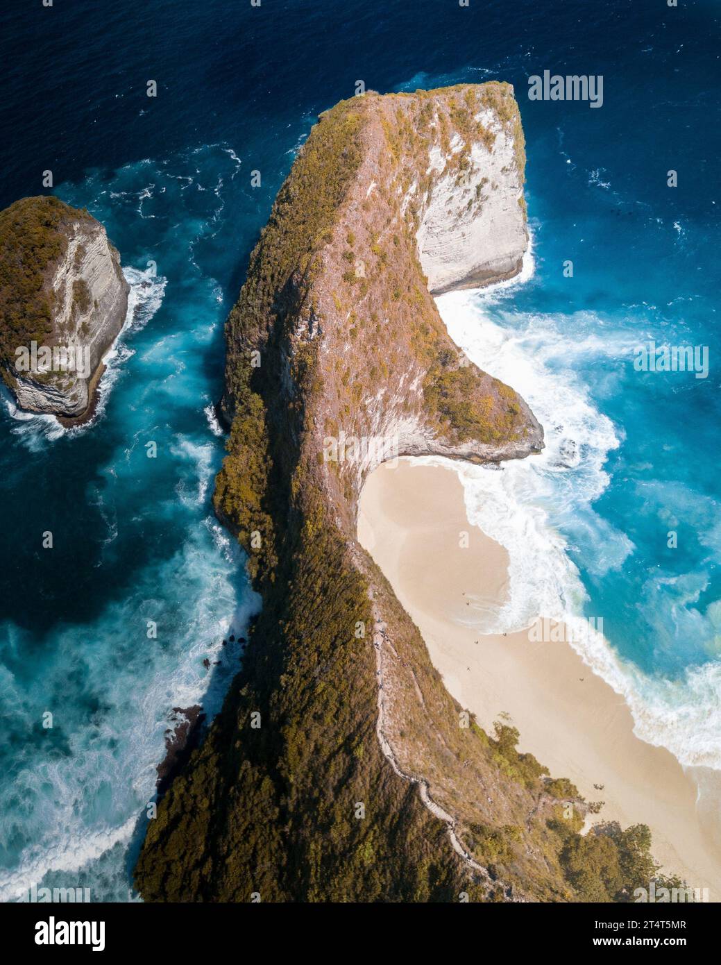 Aerial view of a stunning tropical beach surrounded by towering cliffs ...