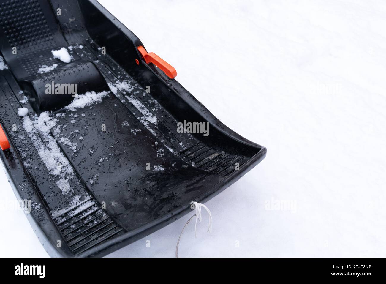 Black plastic sled in the snow Stock Photo - Alamy