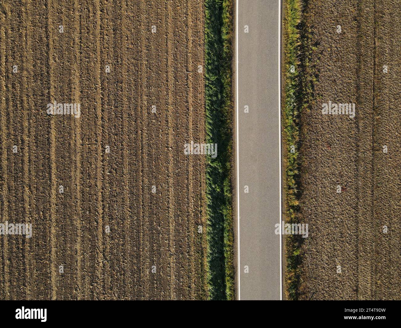 Aerial view of a road between brown agriculture fields with soil in the ...
