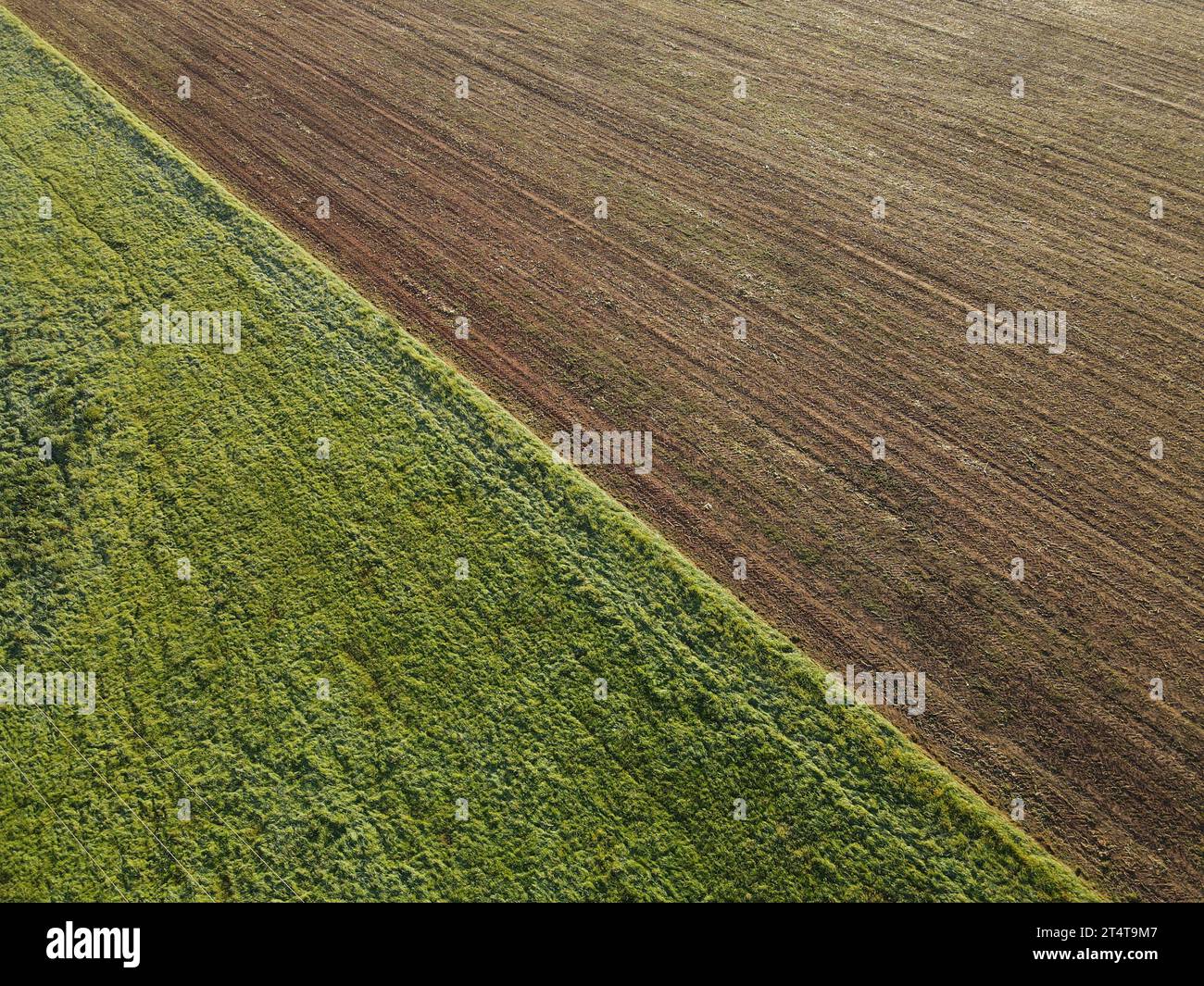 Aerial view of a brown country field with soil and a green country ...