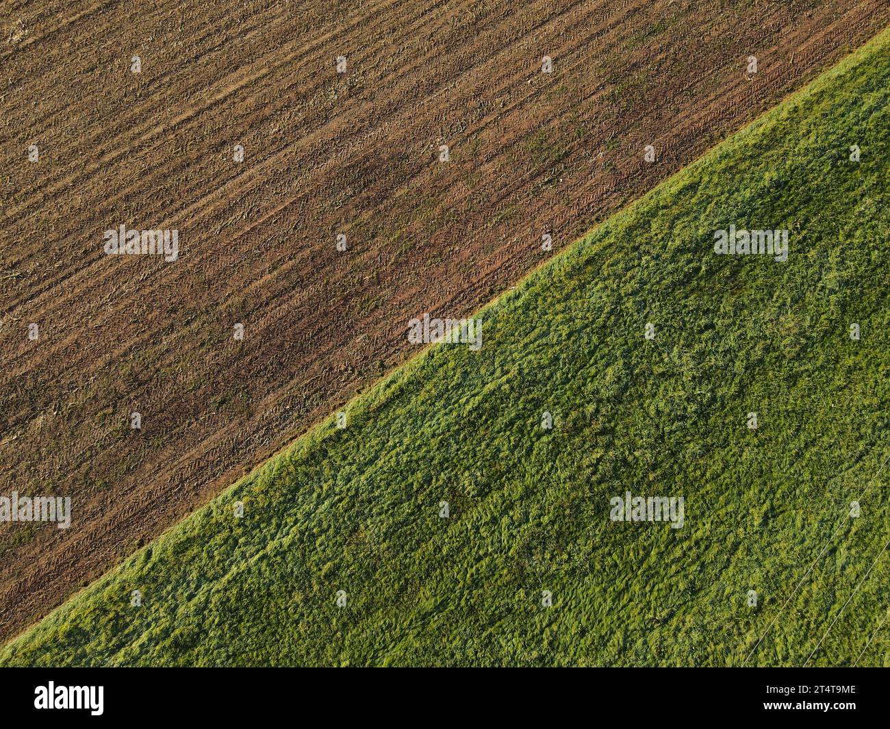 Aerial view of a brown country field with soil and a green country ...