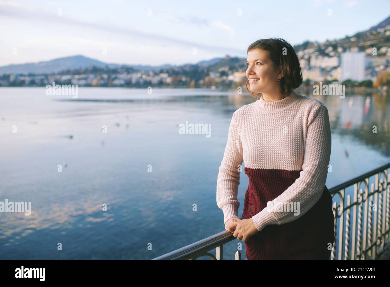 Outdoor portrait of beautiful young woman relaxing by mountain lake ...
