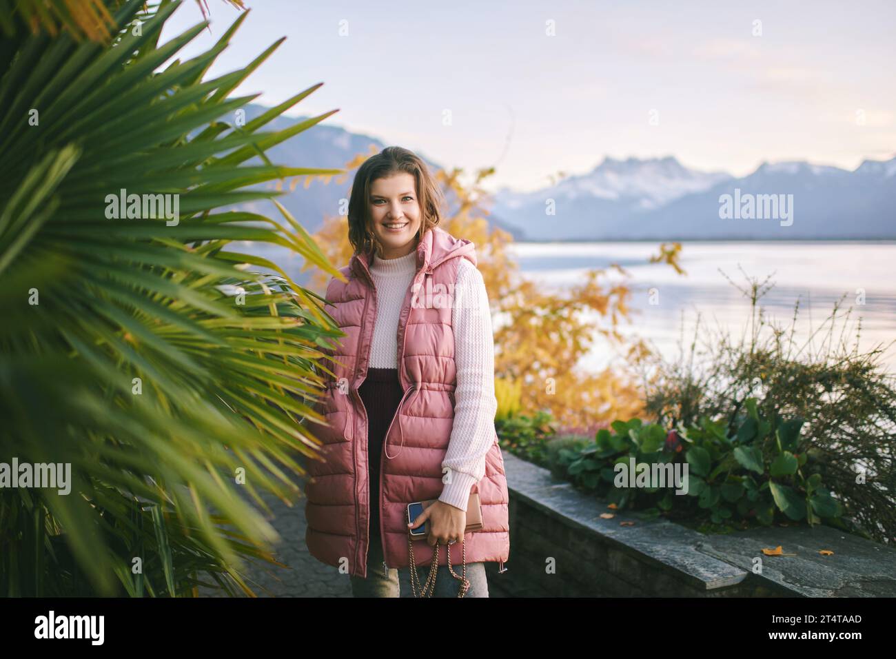 Outdoor portrait of beautiful young woman relaxing by mountain lake ...