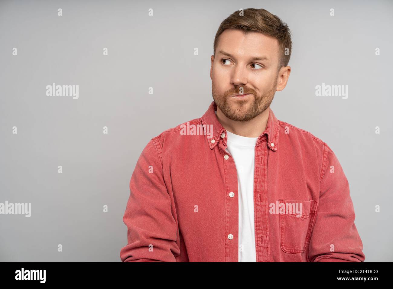 Doubted puzzled man looks suspiciously on copy space isolated on gray ...