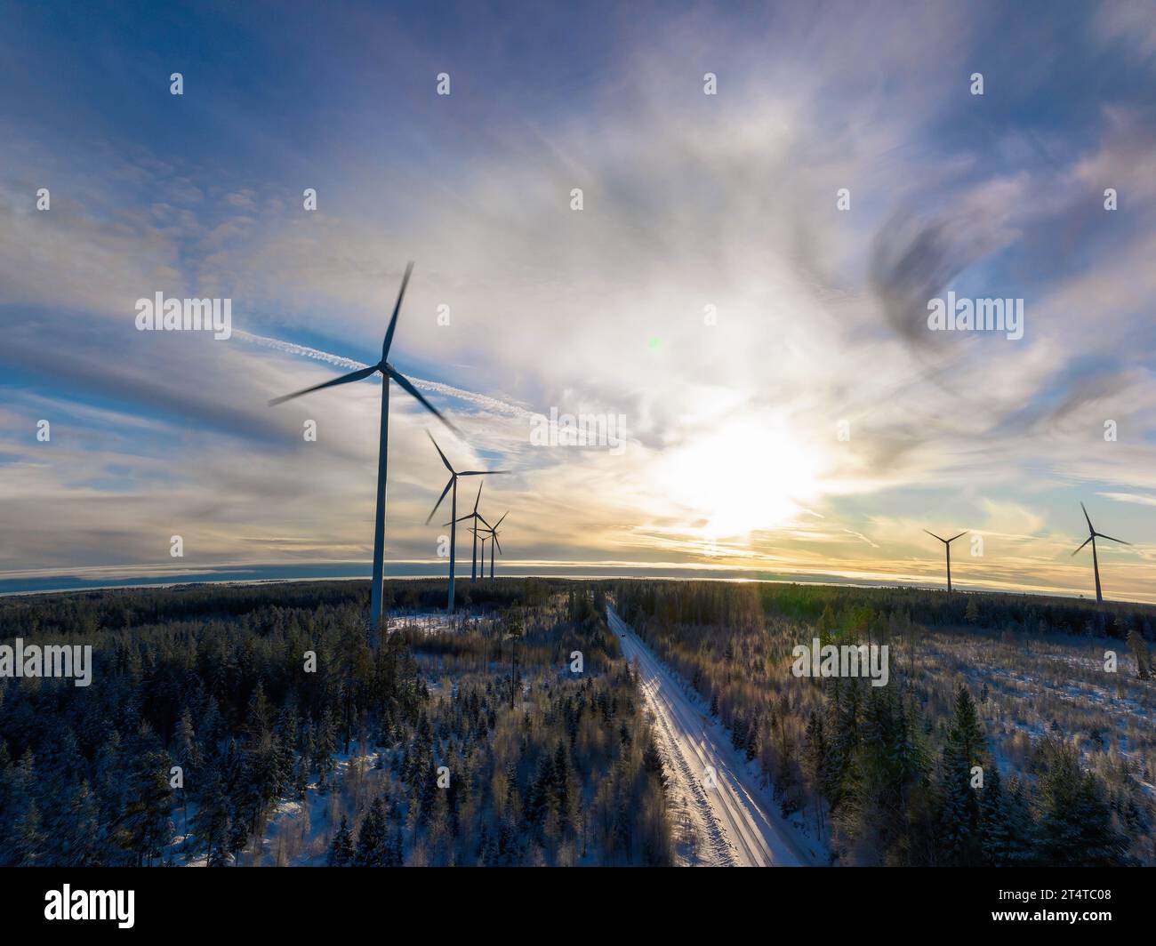 Aerial scenic photo over forest winter road with windmills standing in ...