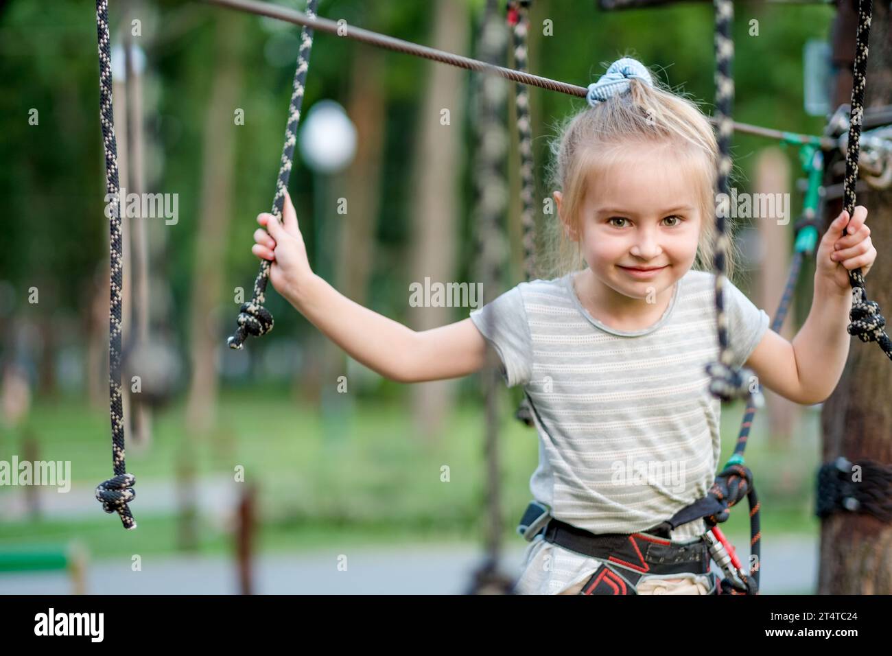 Cute girl enjoying activity in a climbing adventure park. Girl goes on ...
