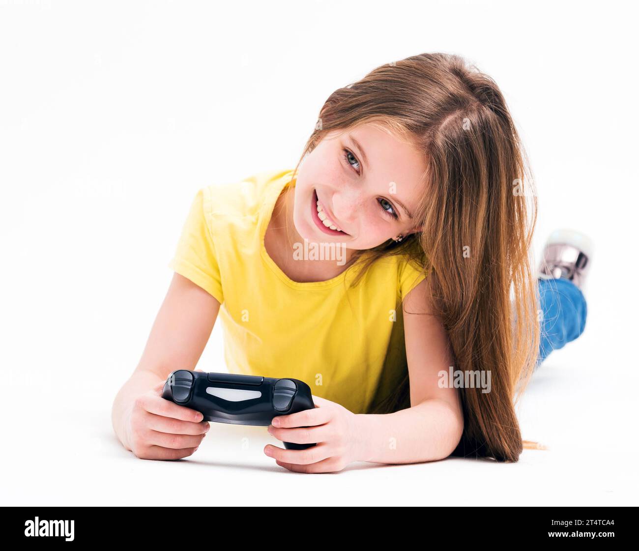 Smiling cute teenage girl lying on the floor, playing on console ...