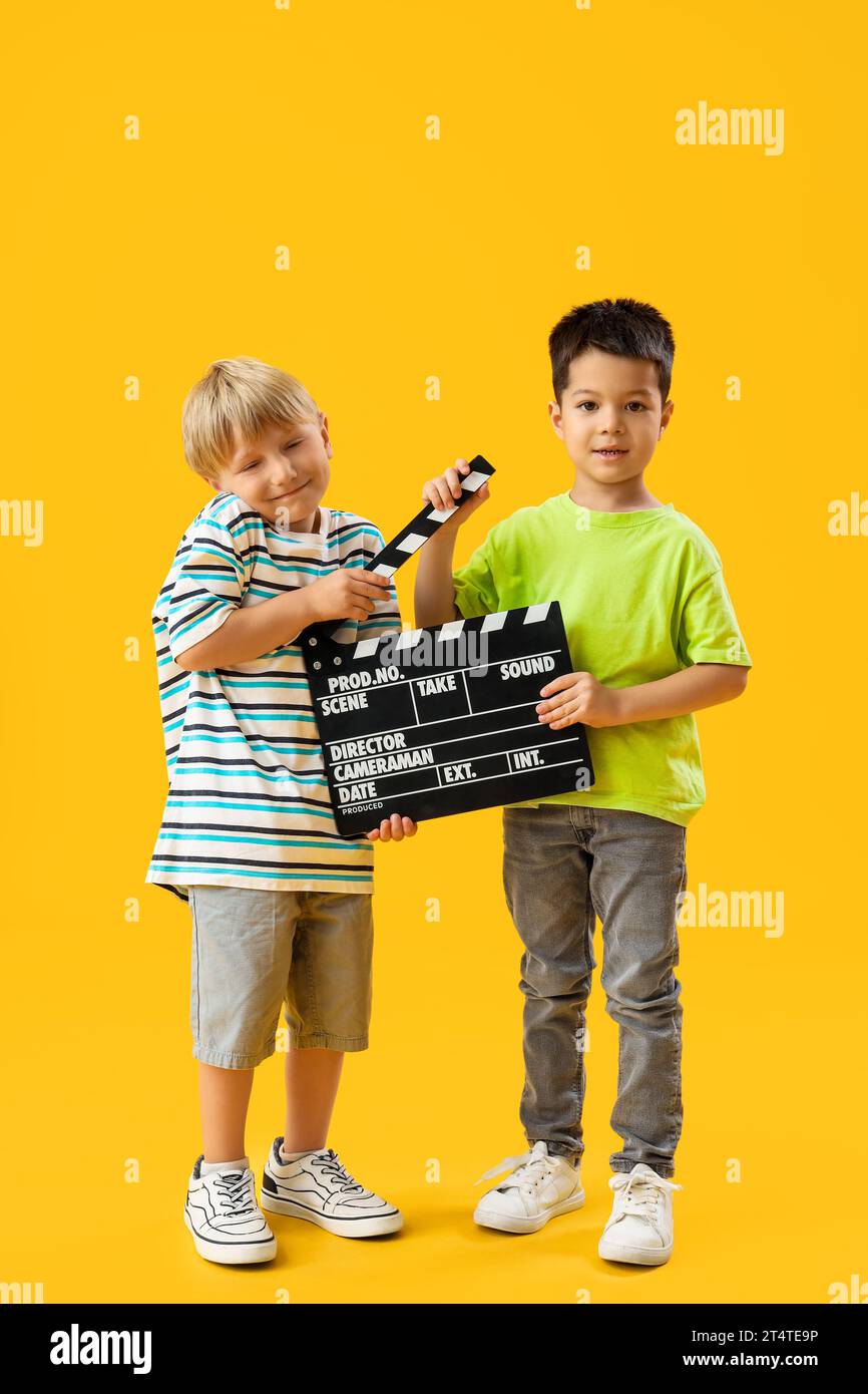 Cute little boys with movie clapper on yellow background Stock Photo ...