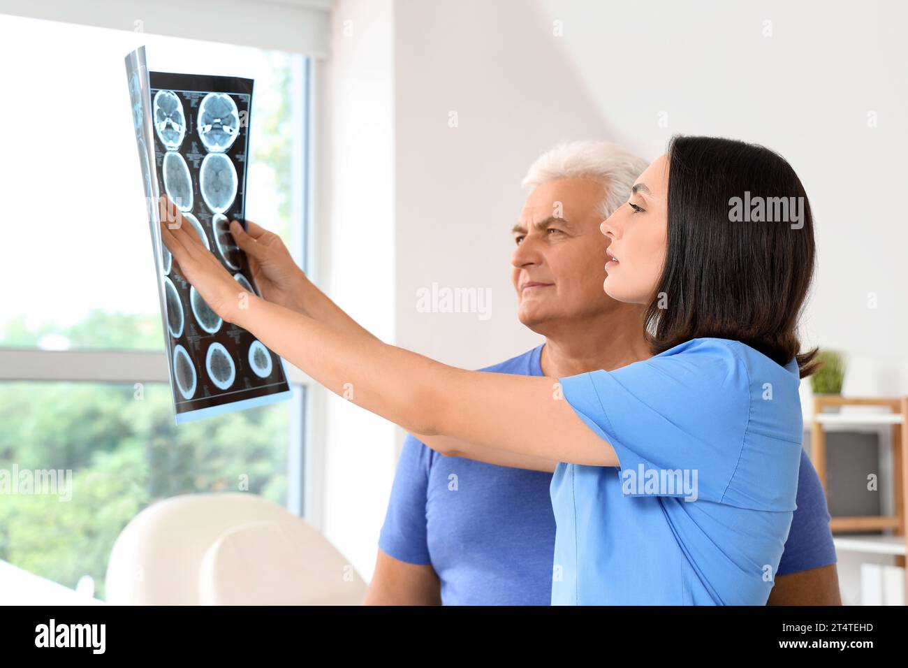 Female doctor showing x-ray scan to senior patient in medical office ...