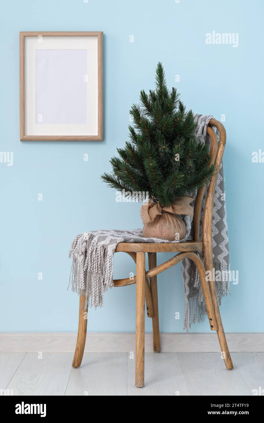 Christmas tree on chair near blue wall with blank frame in room Stock ...