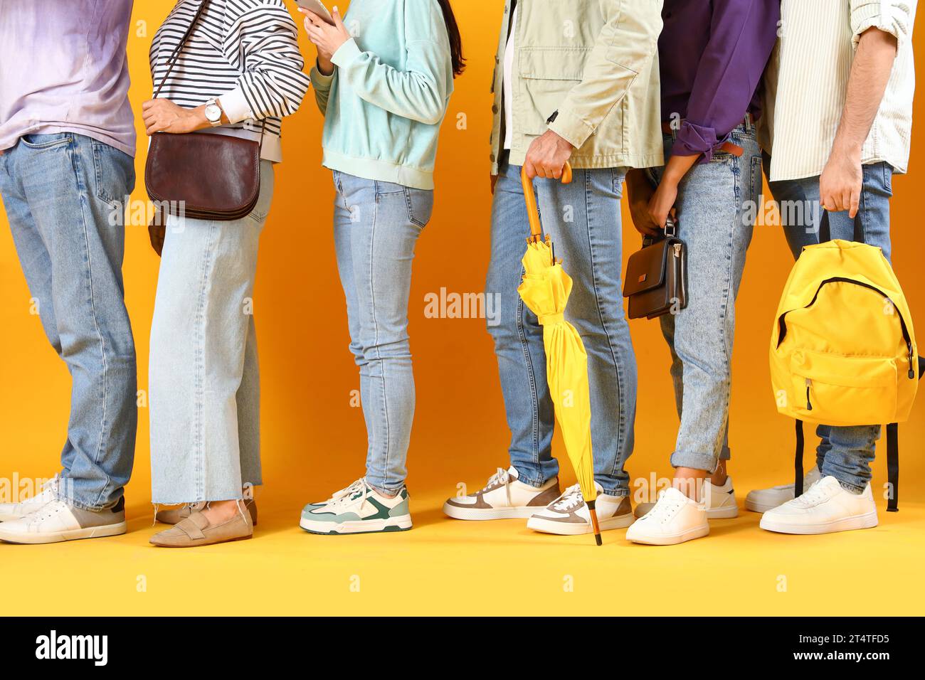 People waiting in line on yellow background Stock Photo - Alamy