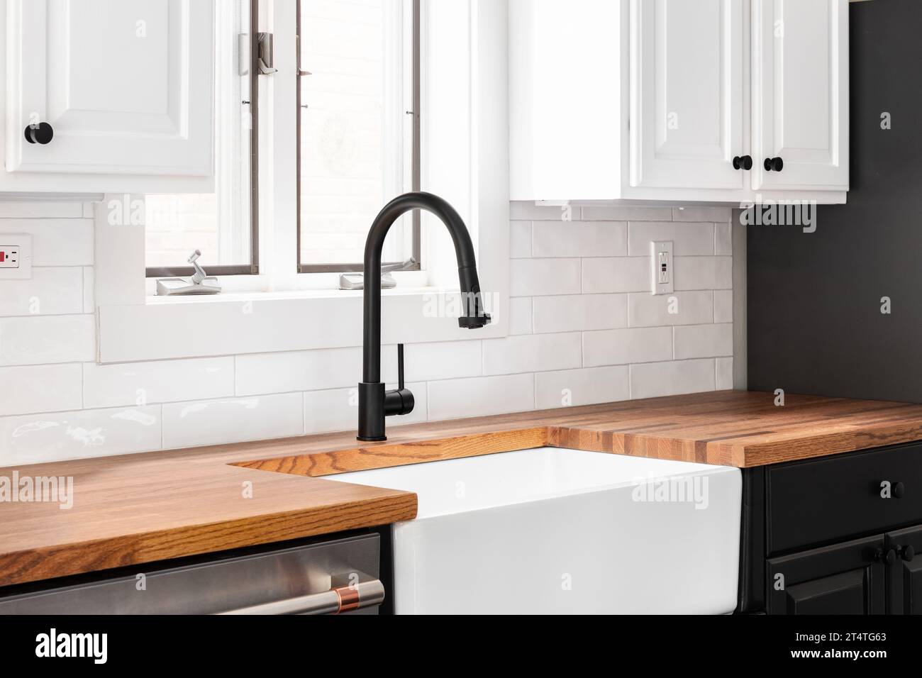 A kitchen faucet detail with white cabinets, a butcher block countertop ...