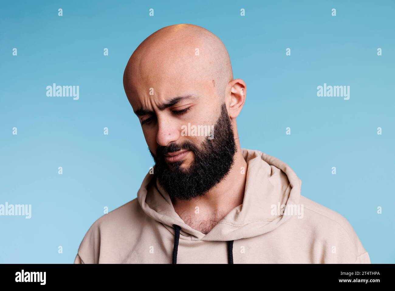 Thoughtful arab man tilting head down and looking away. Young bald ...