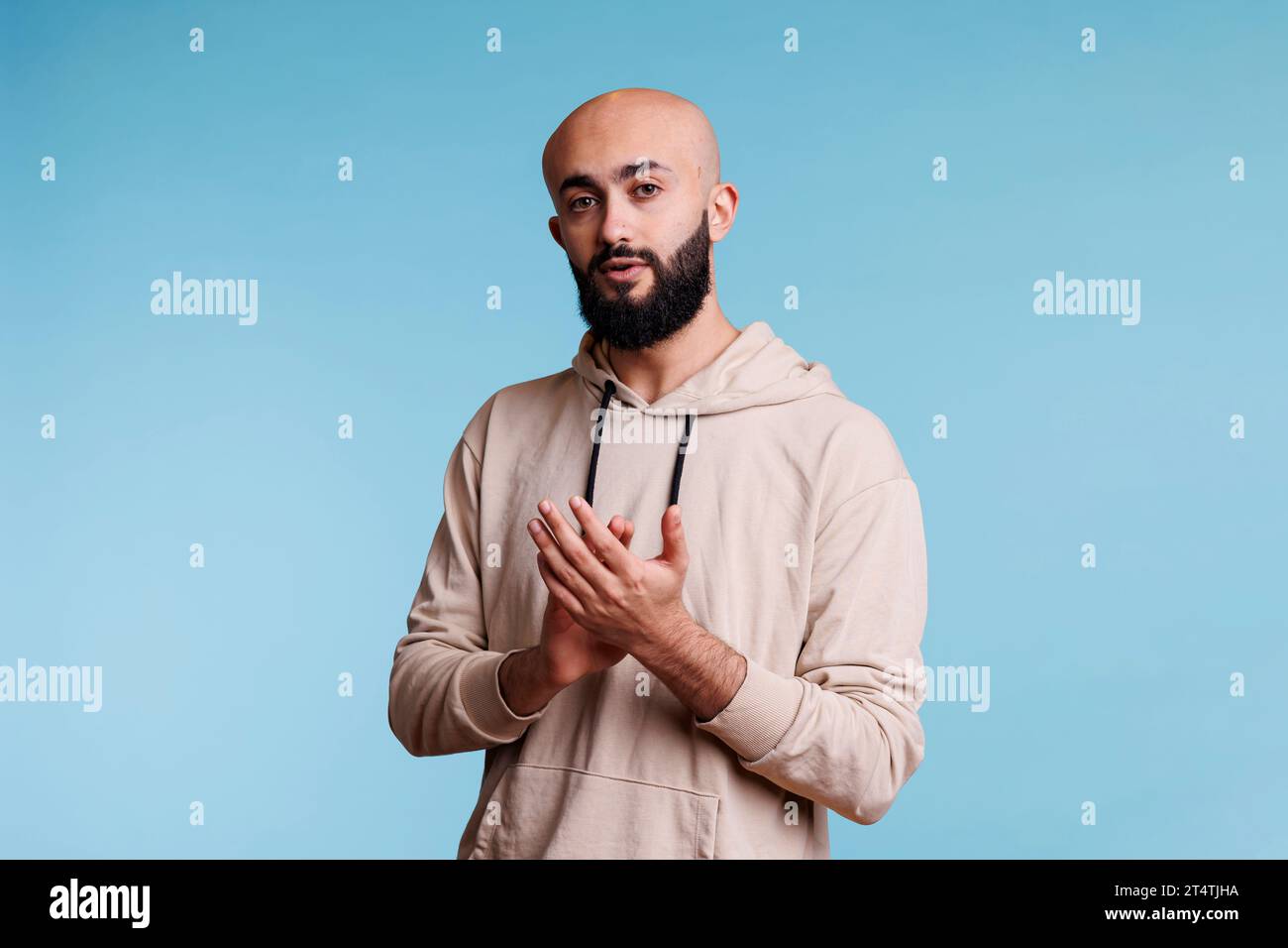 Arab man applauding with hands while standing and looking at camera ...