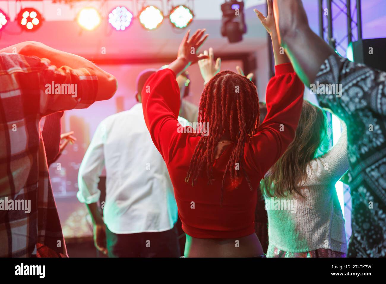 People dancing and raising hands while attending dj party in nightclub ...