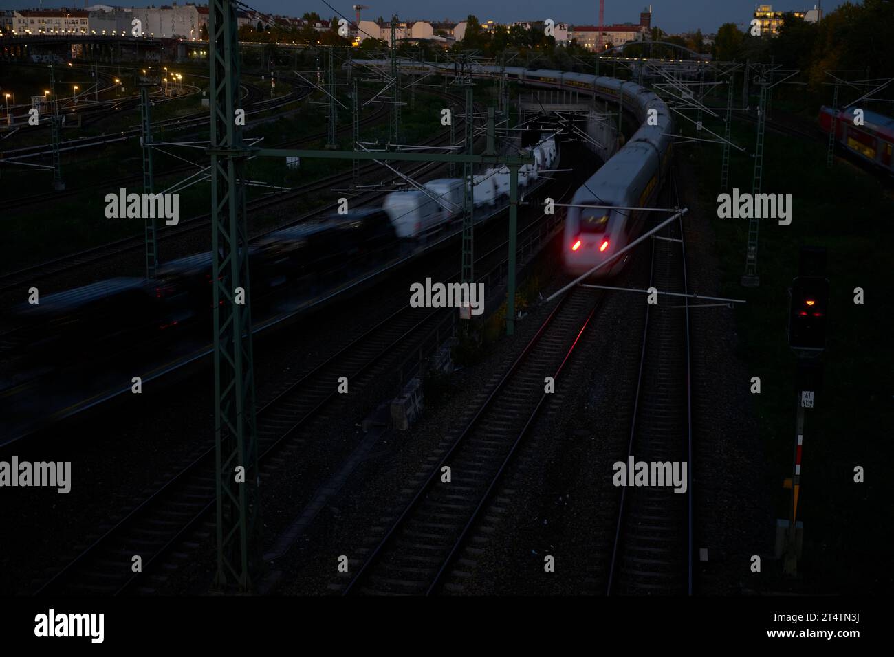 A freight train and passenger trains pass through northern Berlin, Germany 2022, in the evening ...