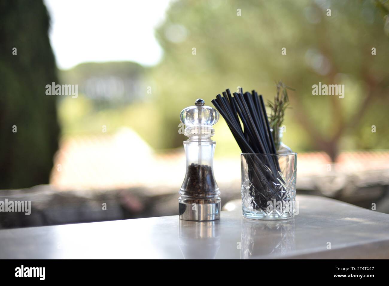 A pair of jars filled with straws and spices sitting on a table in a ...