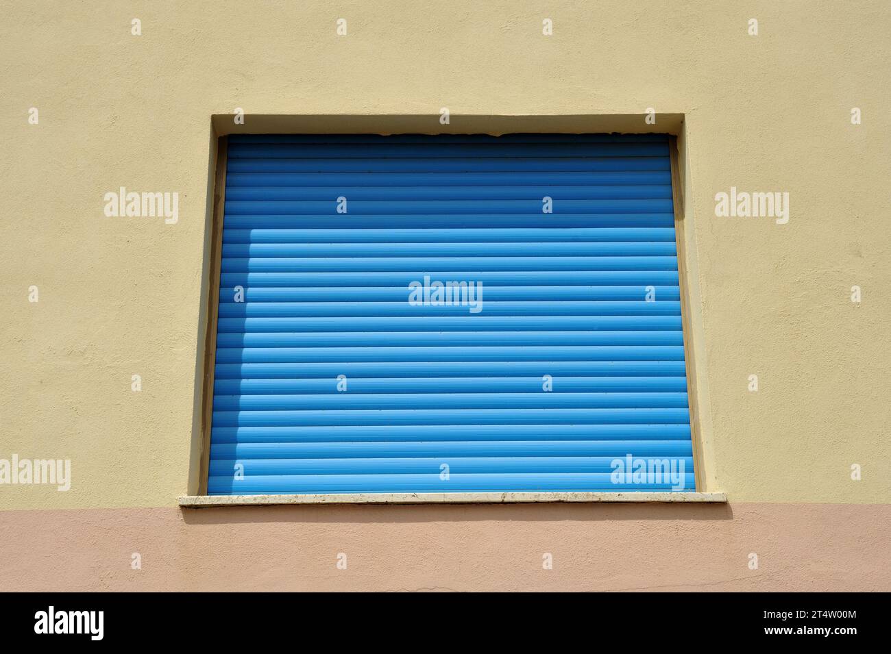 A large building with a blue metal roller shutter closed over the ...