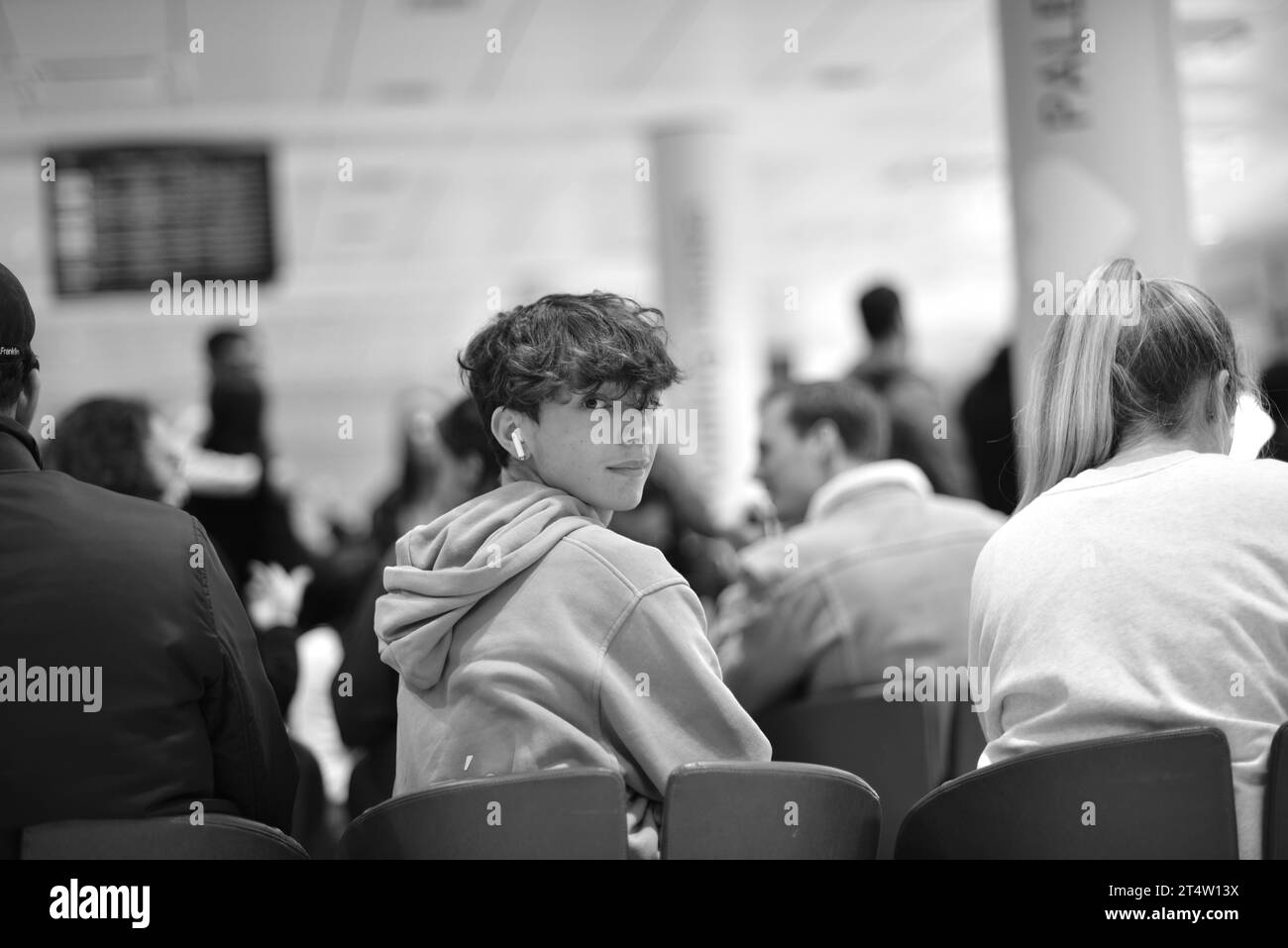 A group of people are seated in a waiting room, anticipation palpable ...