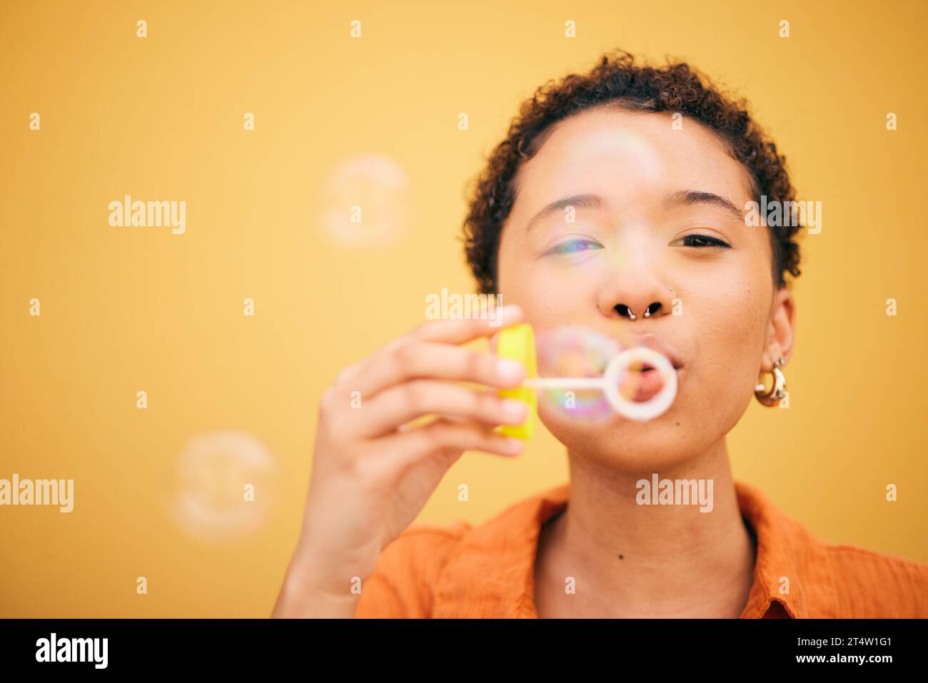Portrait, blowing bubbles and woman in studio for fun, playful or ...