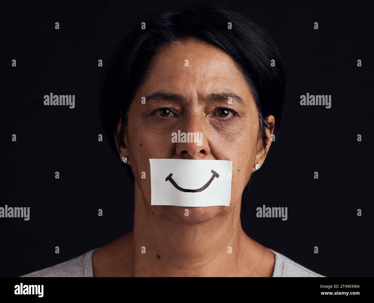 Portrait, fake smile or abuse and a mature woman in studio on a dark ...