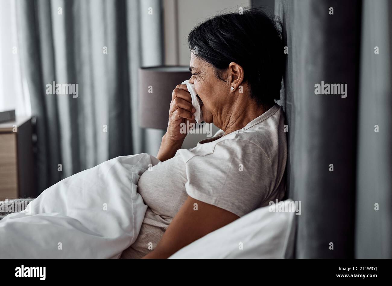 Sick, tissue and elderly woman in bed blowing nose, flu or viral ...