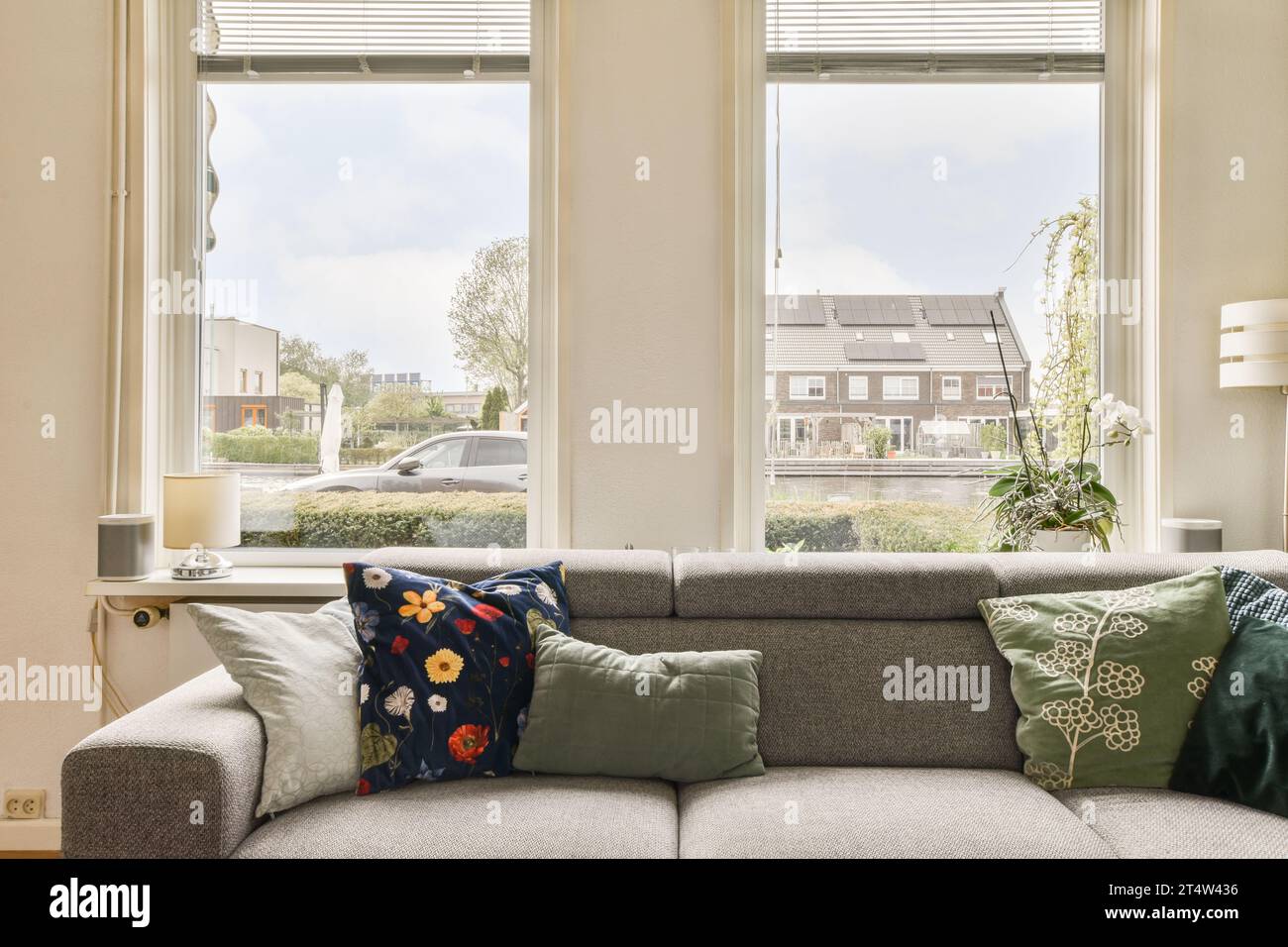 a living room with two large windows, and a couch in front of the ...