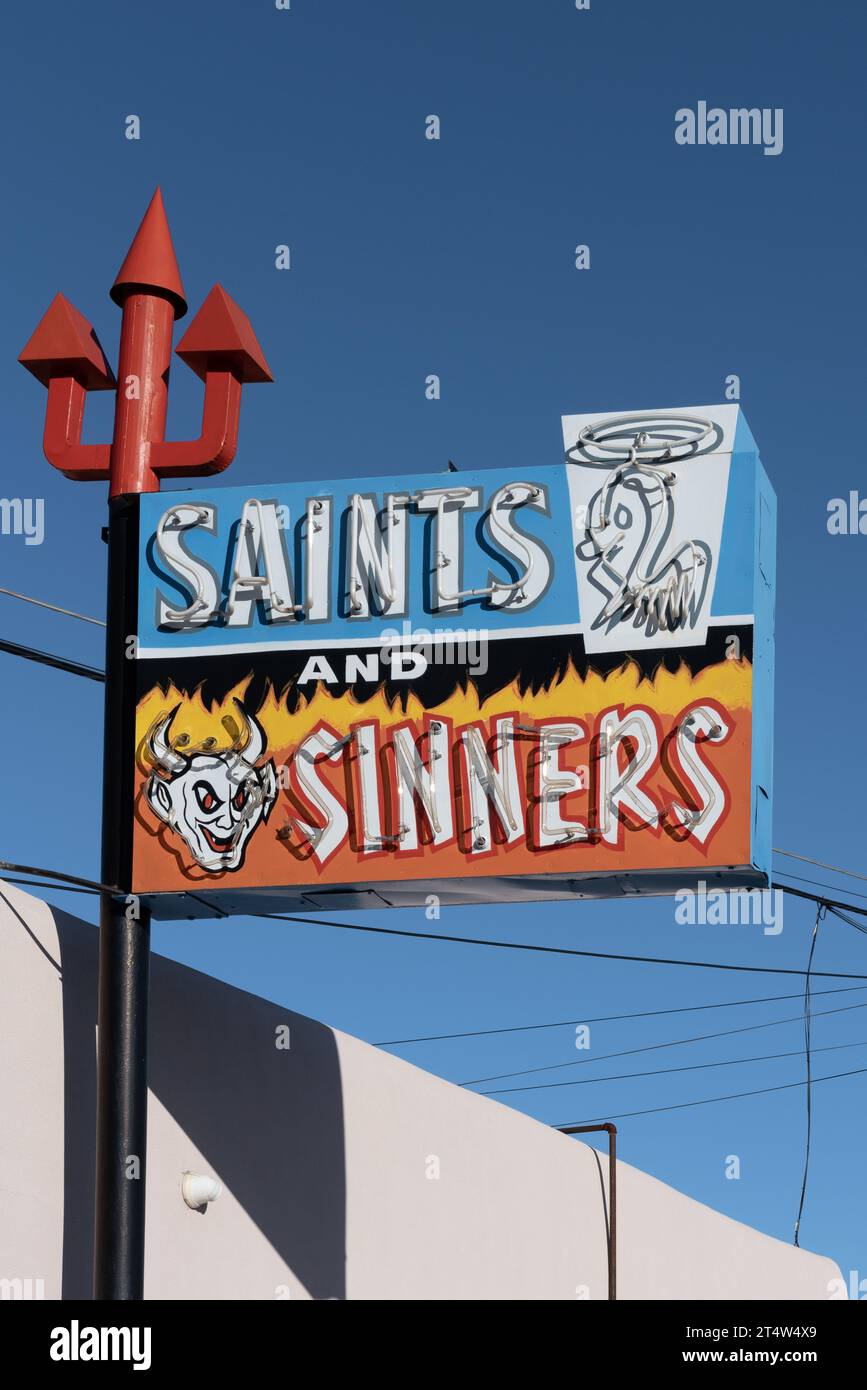 Brightly colored neon sign with a red trident for Saints and Sinners, a ...