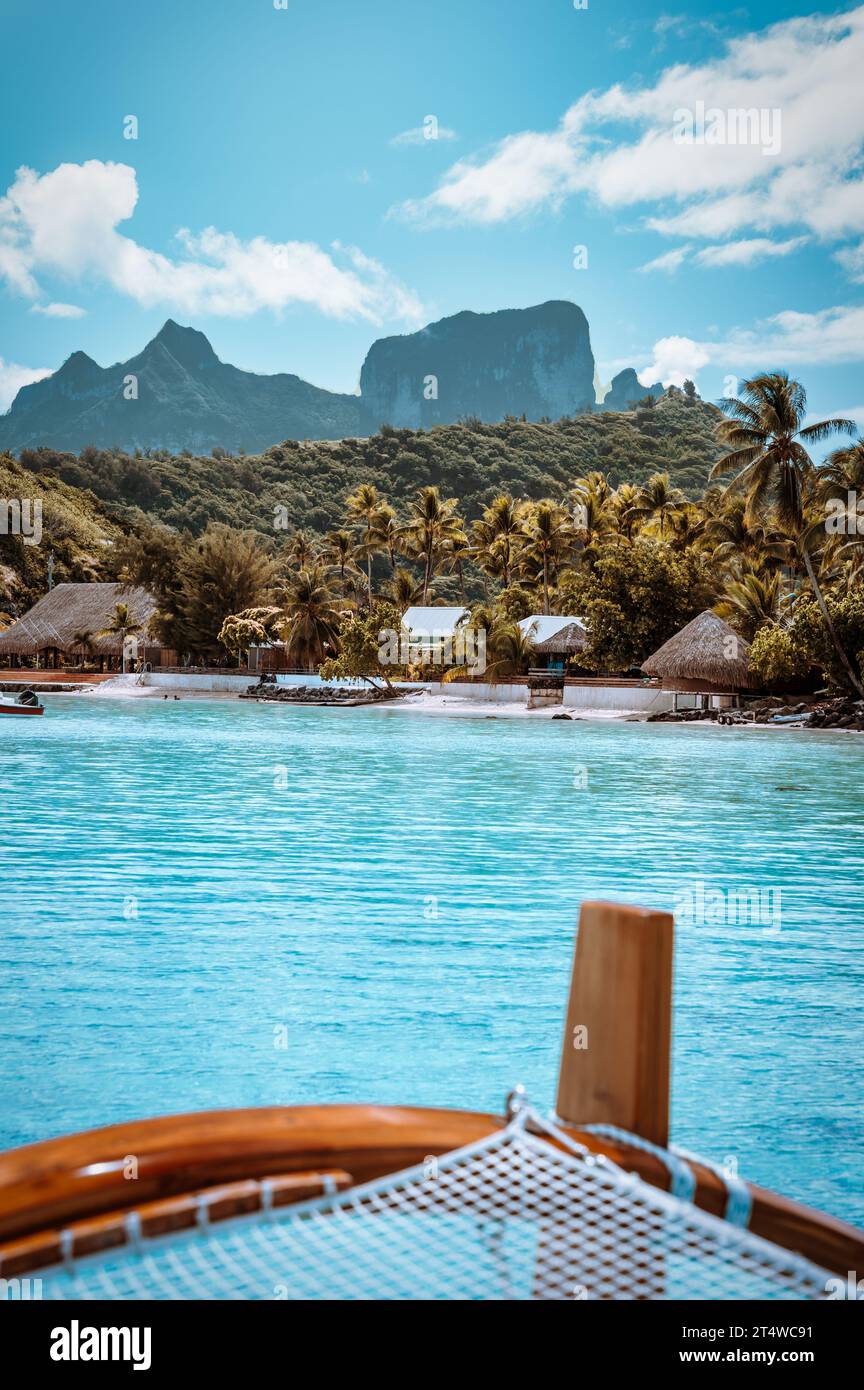 A boat of beach huts in Tahiti, surrounded by lush green vegetation and ...