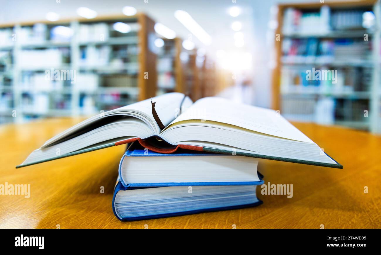Stack of books opened on library desk Stock Photo - Alamy