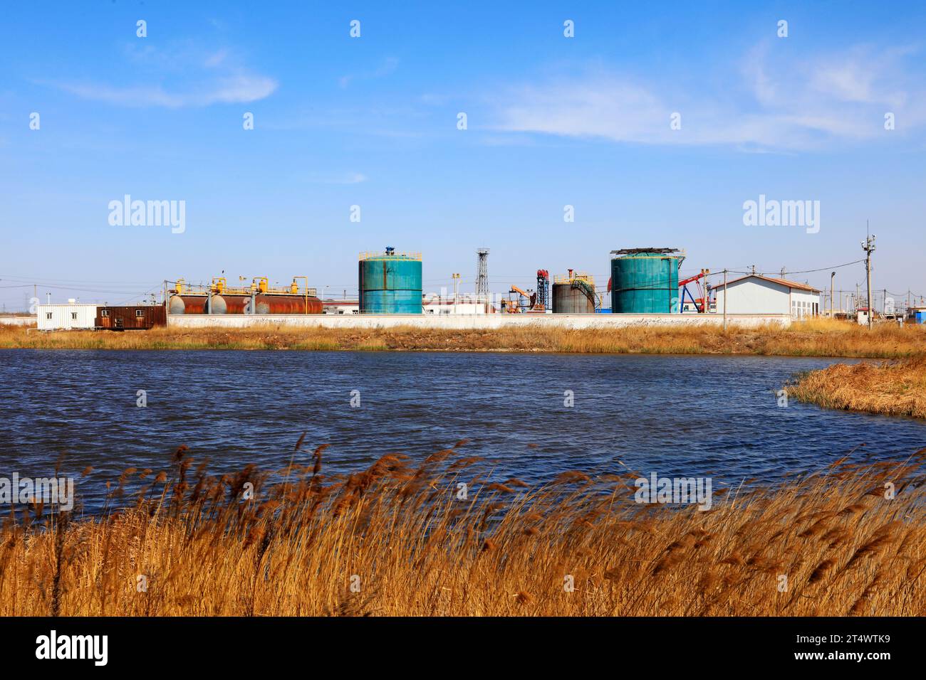 Oil storage tanks and pond under blue sky Stock Photo - Alamy