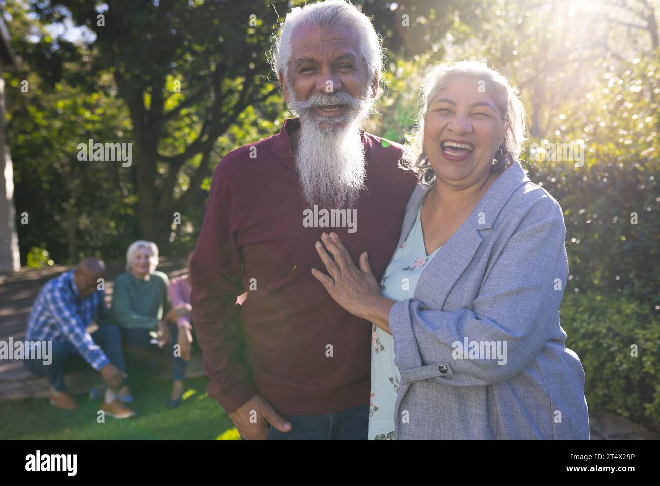 Happy biracial couple of senior friends embracing and smiling in sunny ...